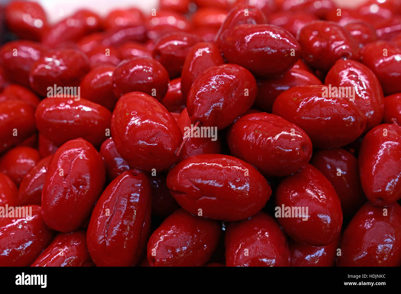 Red whole glossy Italian Cerignola olives in oil close up background ...