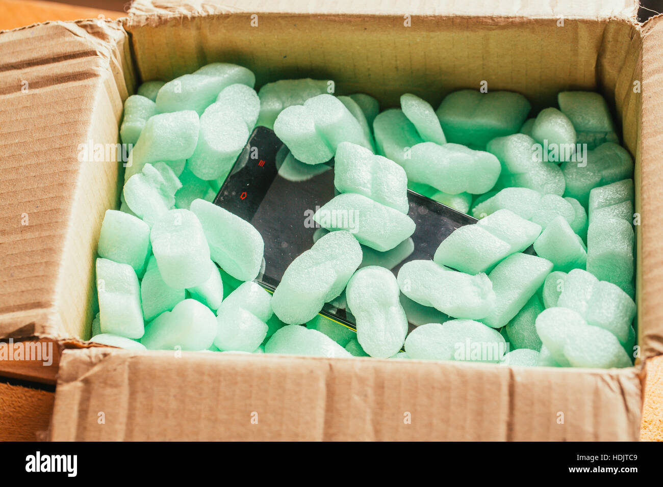 parcel of online shop, phone in a cardboard box on a green styrofoam ...