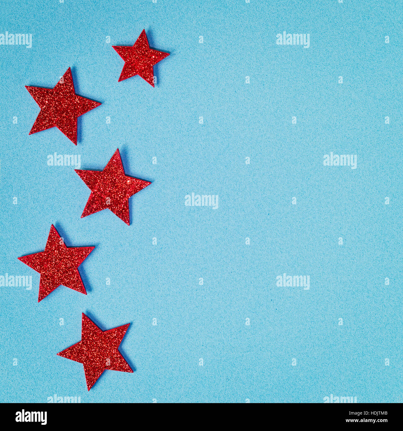 Red shining stars on the left side of a light blue textured background ...