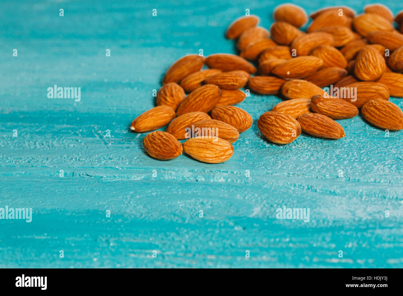 handful of almonds on a blue wooden background Stock Photo - Alamy