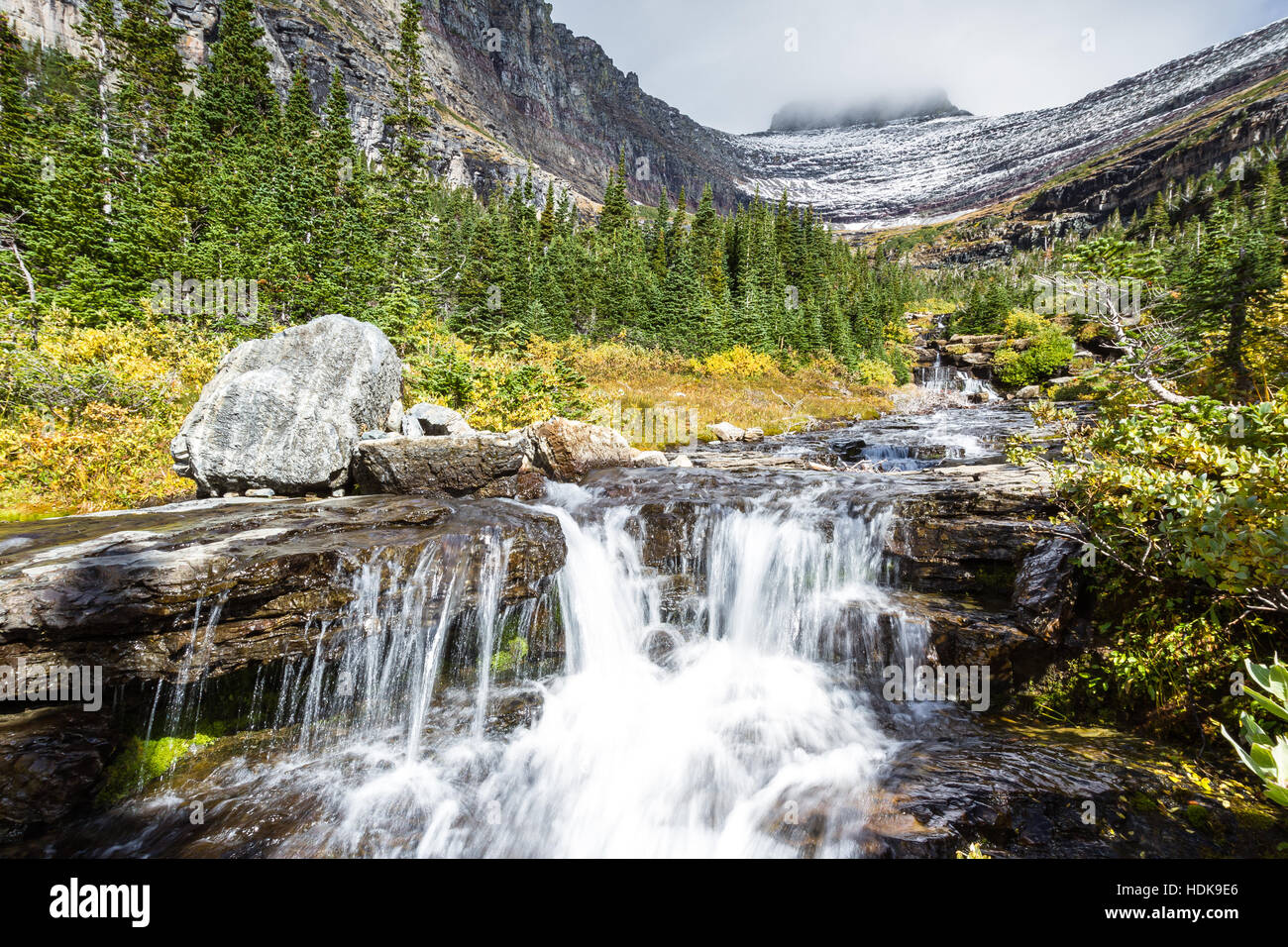 beautiful water fall rising over rocks with golden autumn leaves int he ...