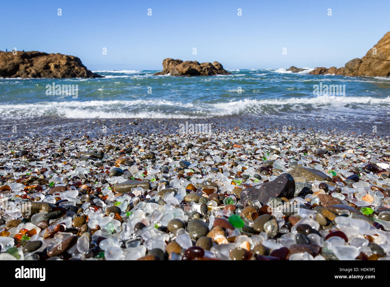 Beautiful sea glass in a variety of colors with blue waves and sky in ...