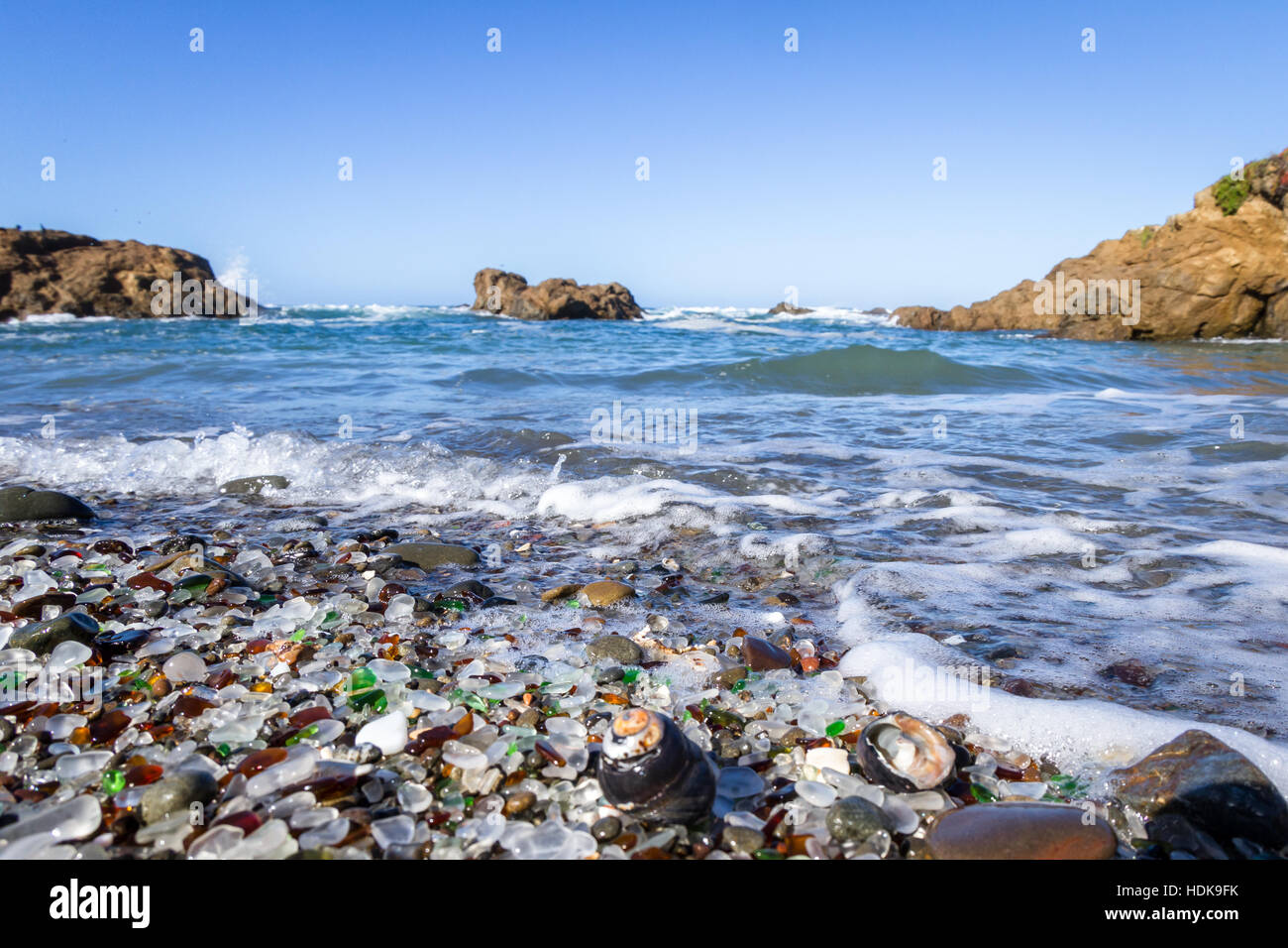 Beautiful sea glass in a variety of colors with blue waves and sky in ...