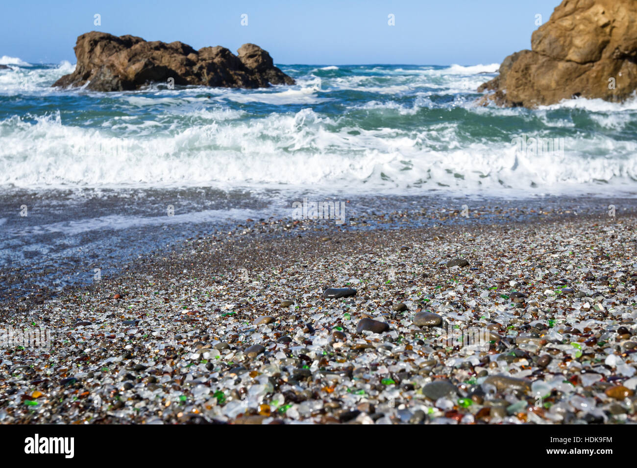 Beautiful sea glass in a variety of colors with blue waves and sky in ...