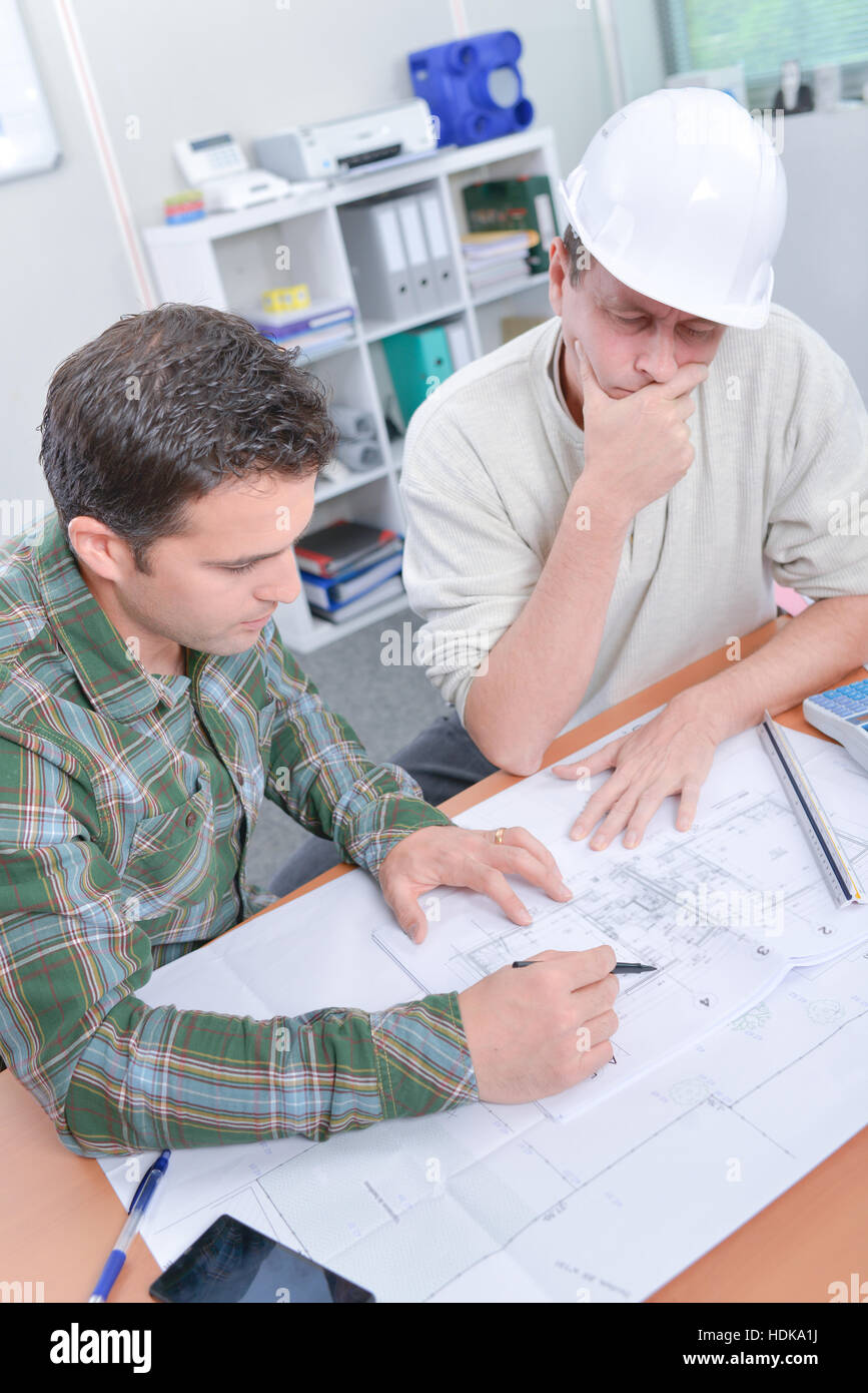 Two men in hardhats looking at blueprints Stock Photo - Alamy