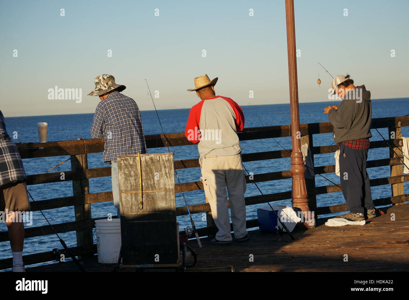 Three fisherman on the pier Stock Photo - Alamy