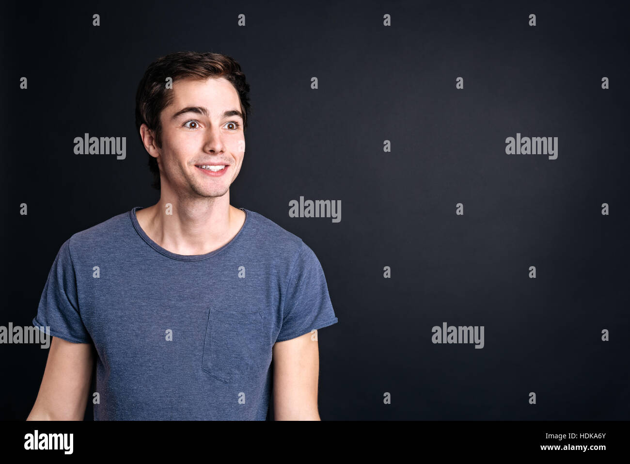 Positively impressed man standing on black background Stock Photo - Alamy