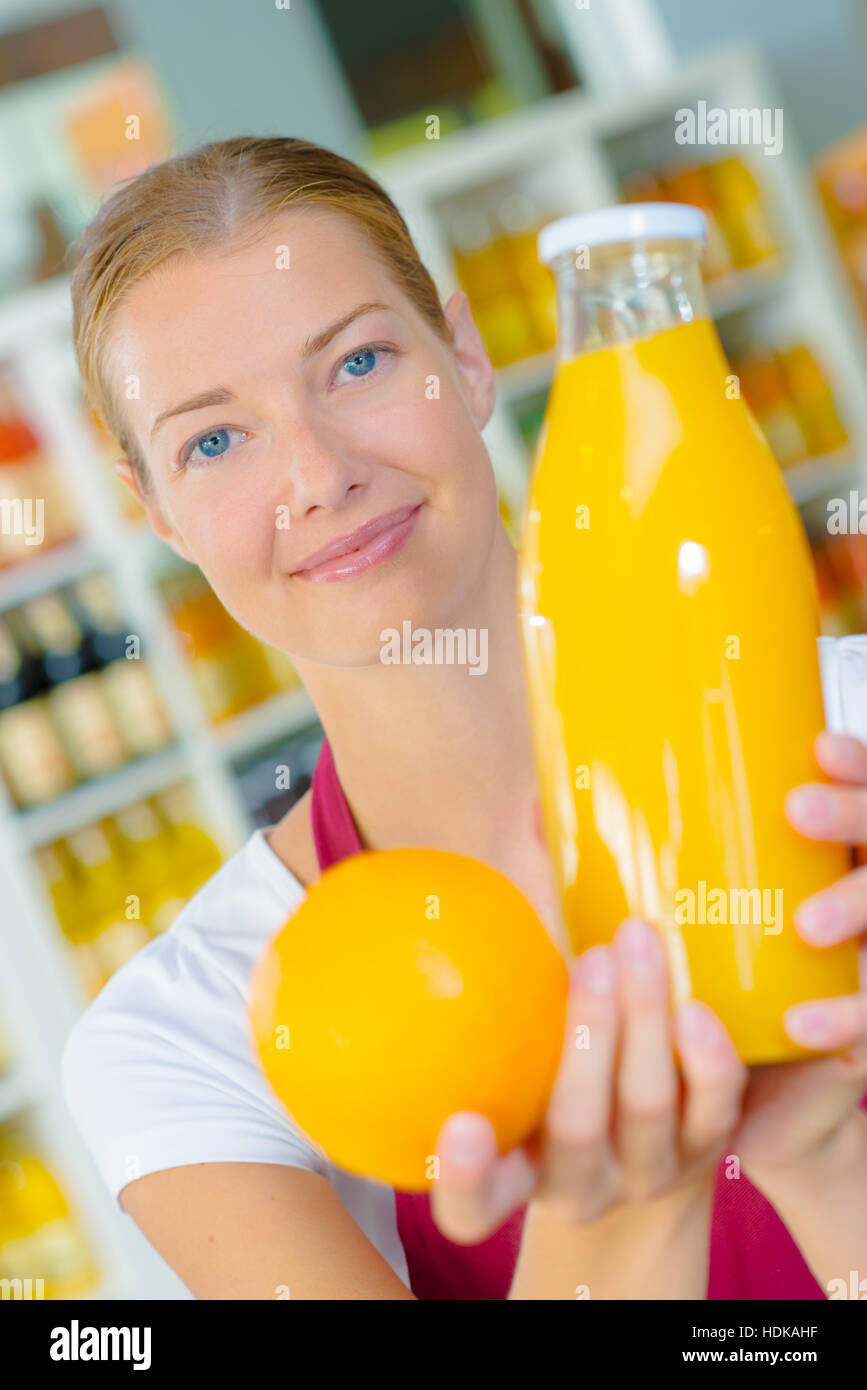 Shop assistant holding an orange and a bottle of orange juice Stock ...