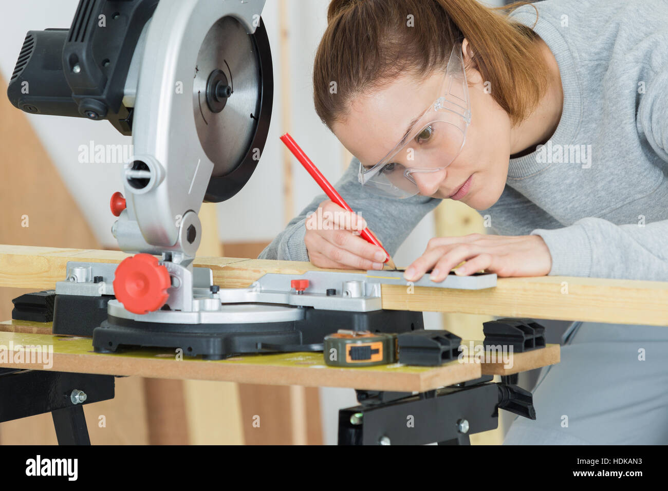 Female worker marking where to cut wood with circular saw Stock Photo ...