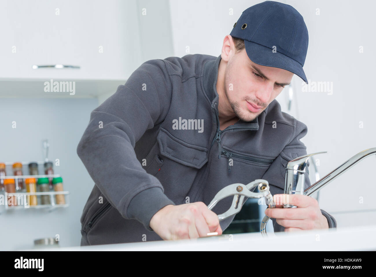 handsome young plumber fixing tap at cleints home Stock Photo - Alamy