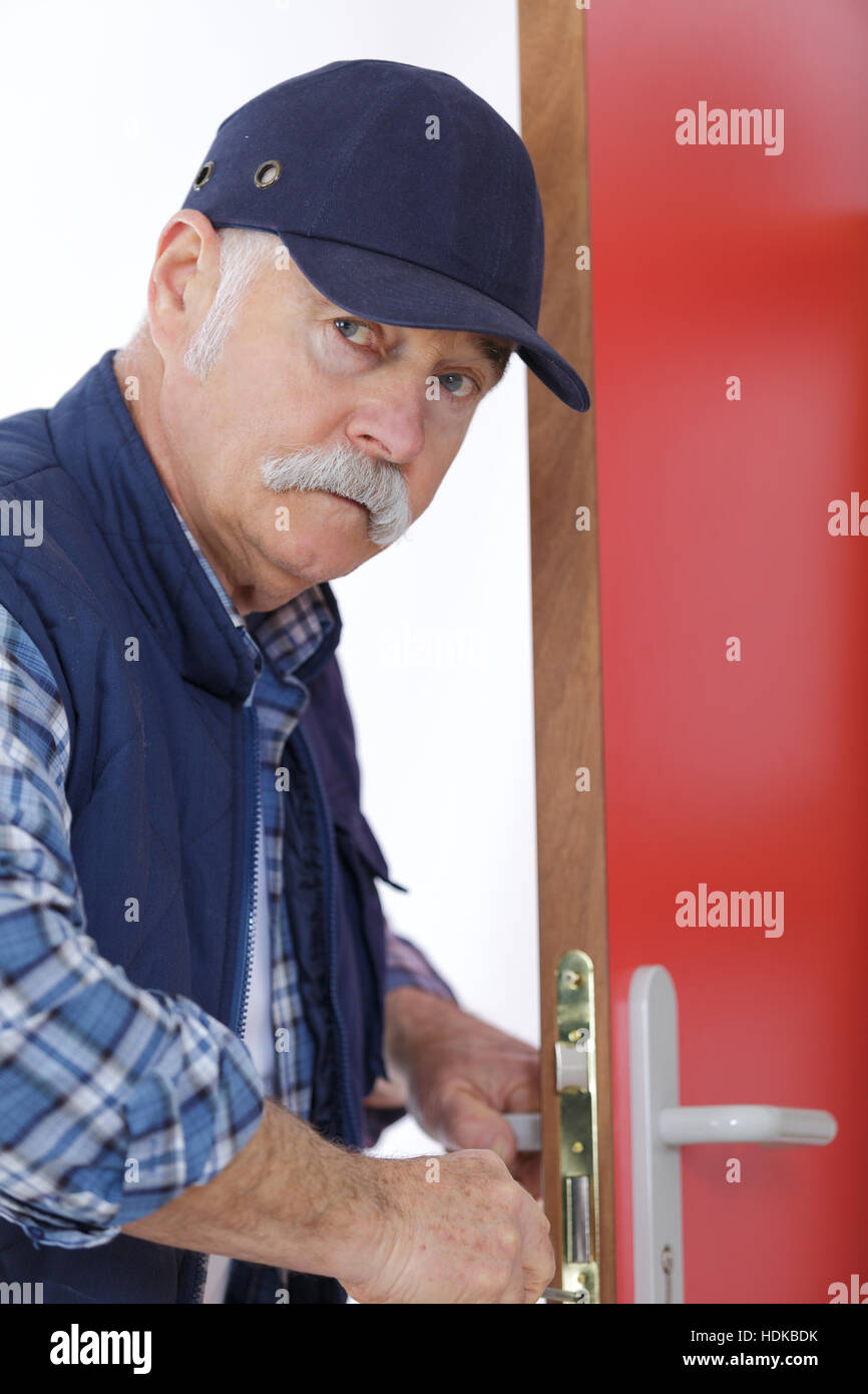 male carpenter fixing lock in door Stock Photo - Alamy