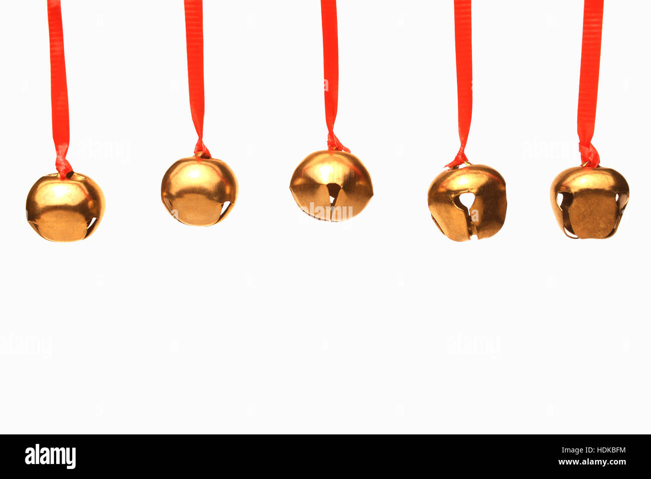 Five jingle bells hanging from red ribbons against white background ...
