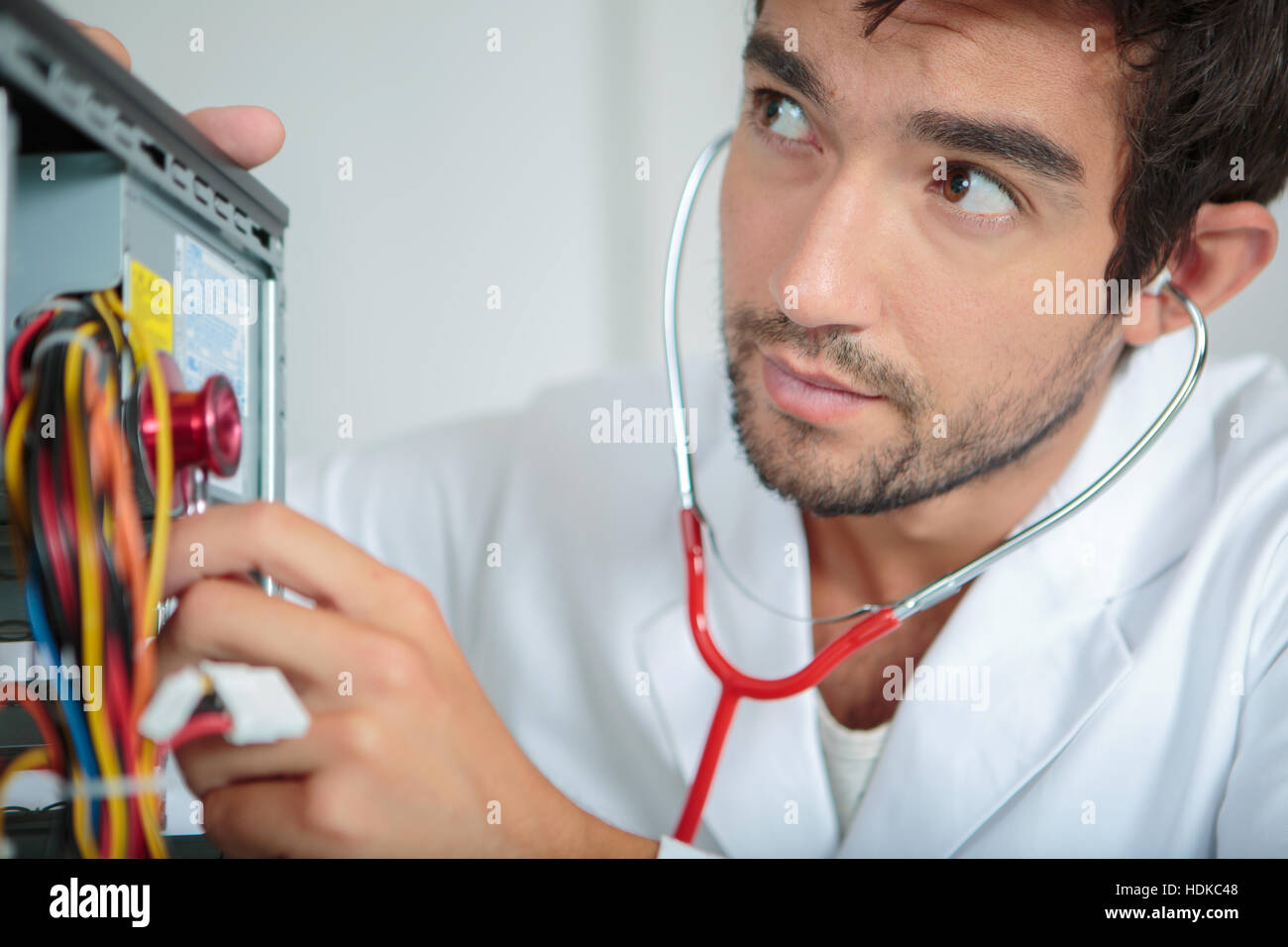 Computer repairman holding stethoscope to computer Stock Photo - Alamy
