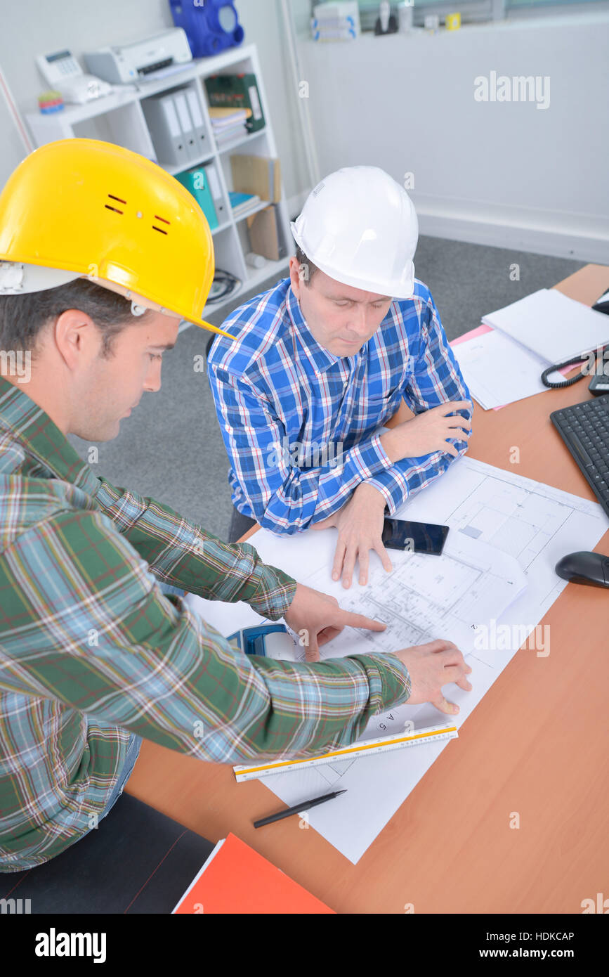 Architects gathered around plans Stock Photo - Alamy