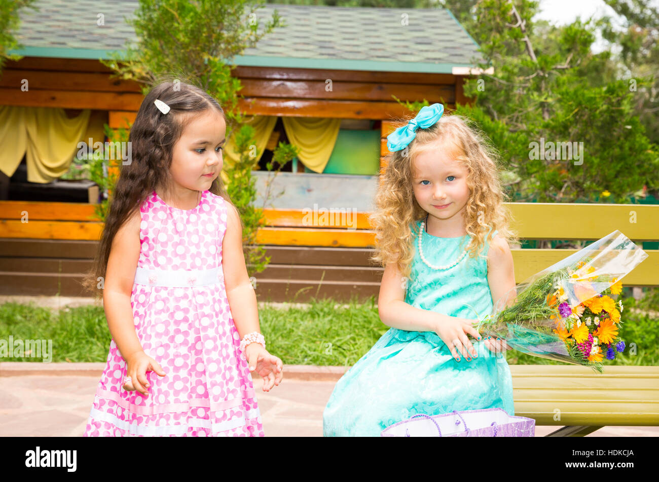Two girlfriends. Adorable little children with bouquet of flowers on ...