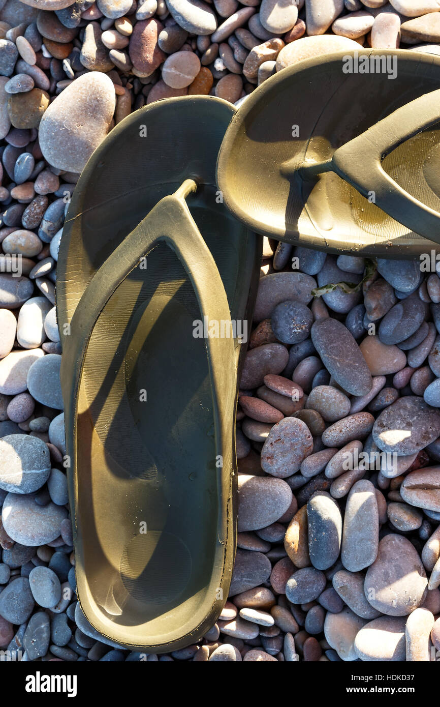 Green Flip Flops on a stones beach. Vertical image Stock Photo - Alamy