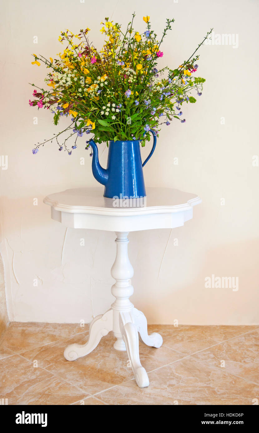 Field flowers in blue vase on white table in front of white wall Stock ...