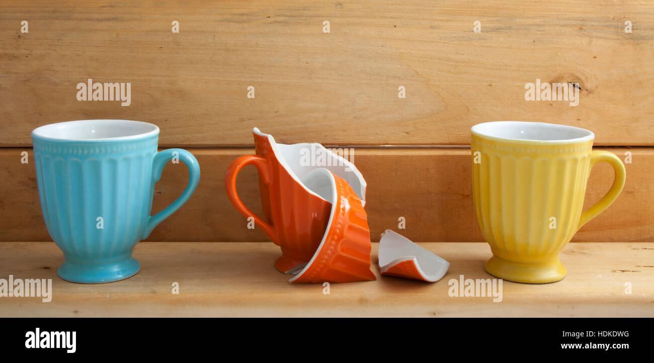Three colorful cups in a row on a wooden shelf Stock Photo - Alamy