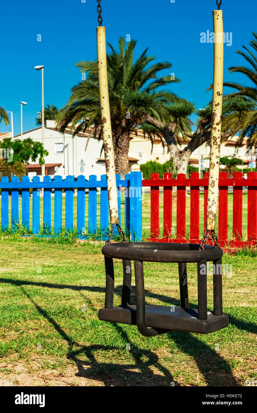 Swing in the playground with colored fences in the background. Vertical ...