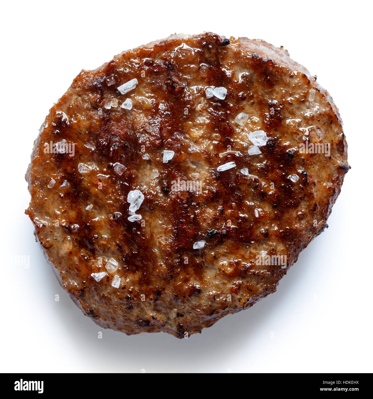 Single grilled hamburger patty with salt isolated on white from above ...