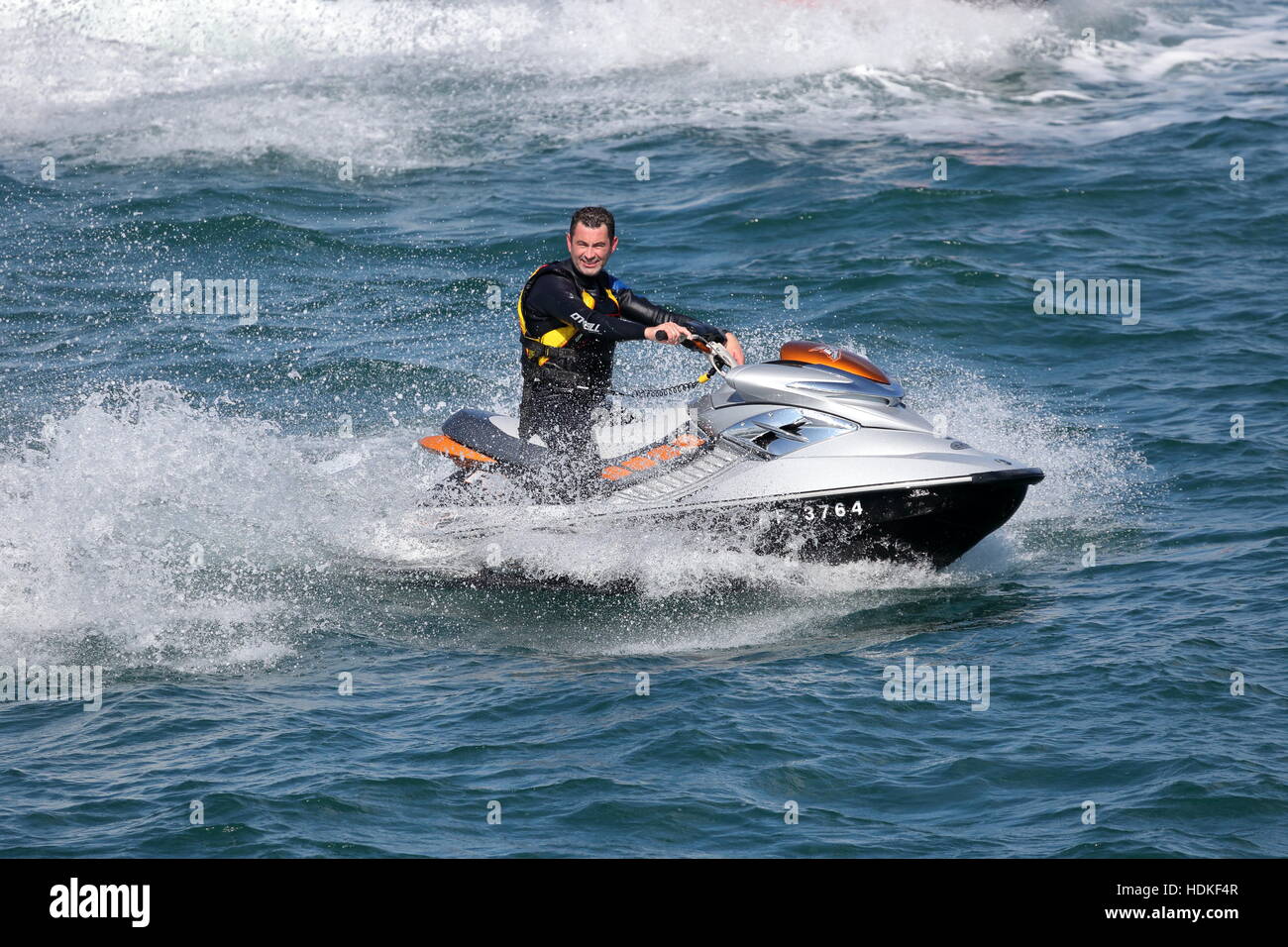Man riding jet ski at speed face on with broad smile and plenty of ...