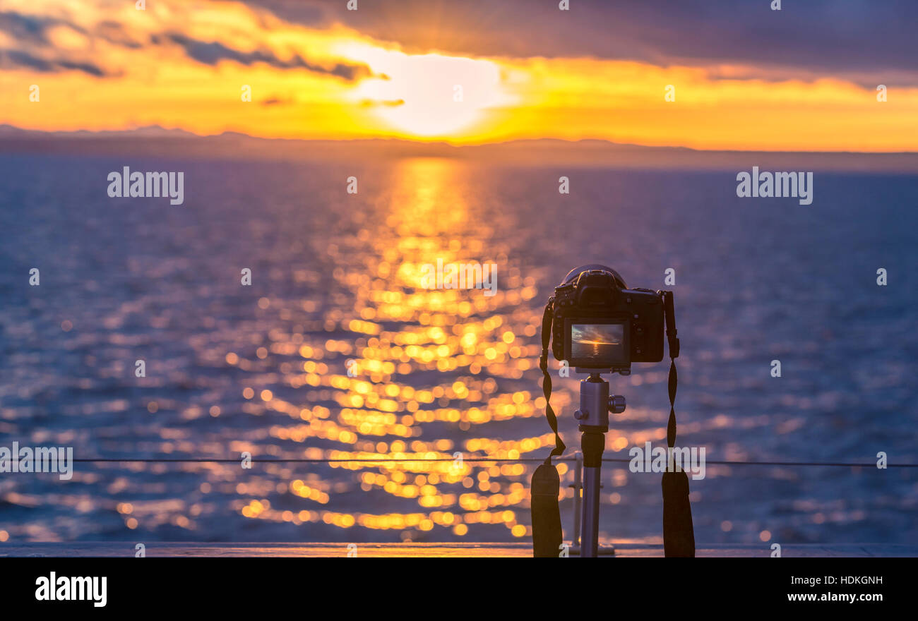A high-performance DSLR camera mounted on a tripod, while the sun is ...
