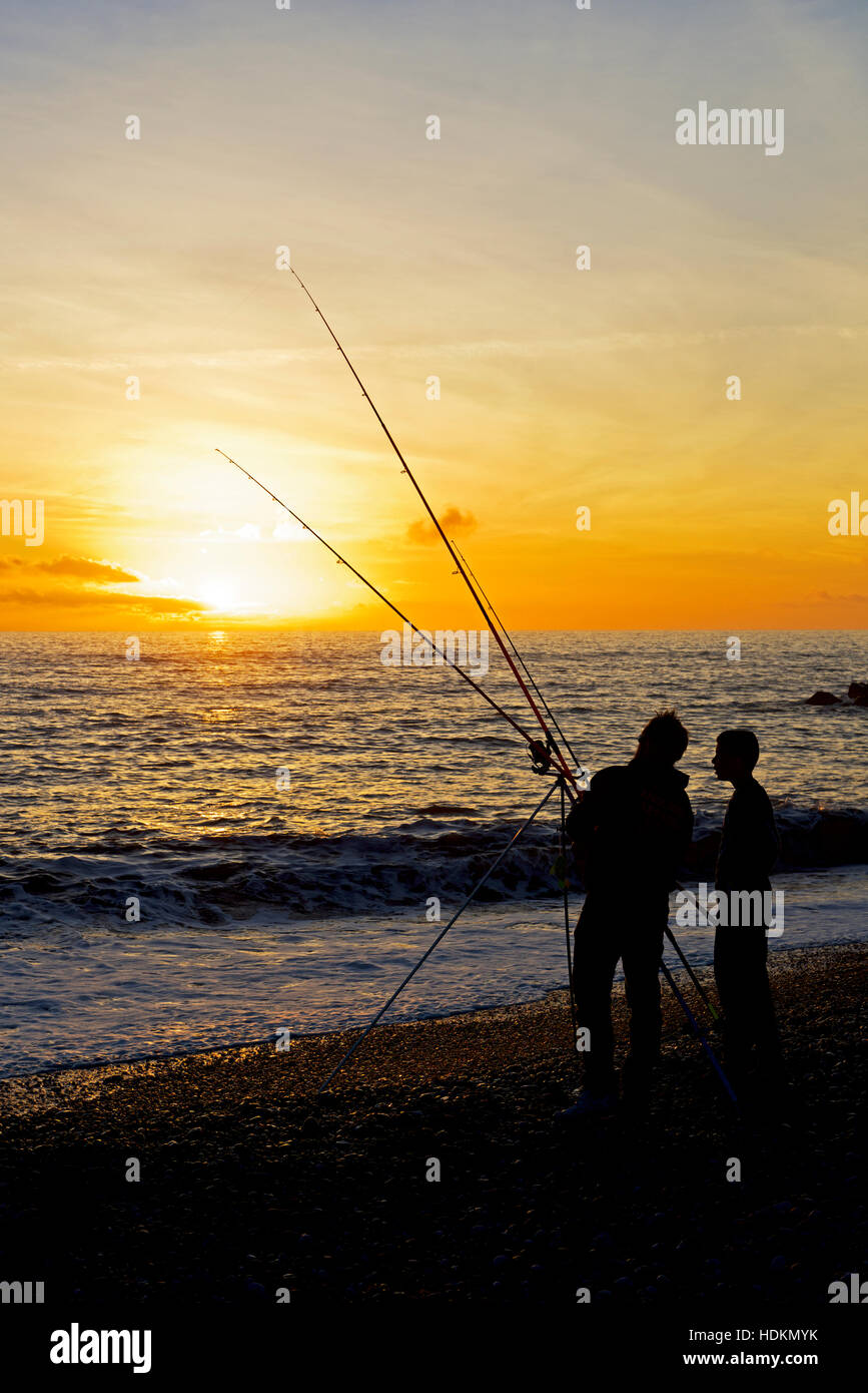 Man and boy fishing on the beach at sunset, West Bay, Bridport, Dorset ...