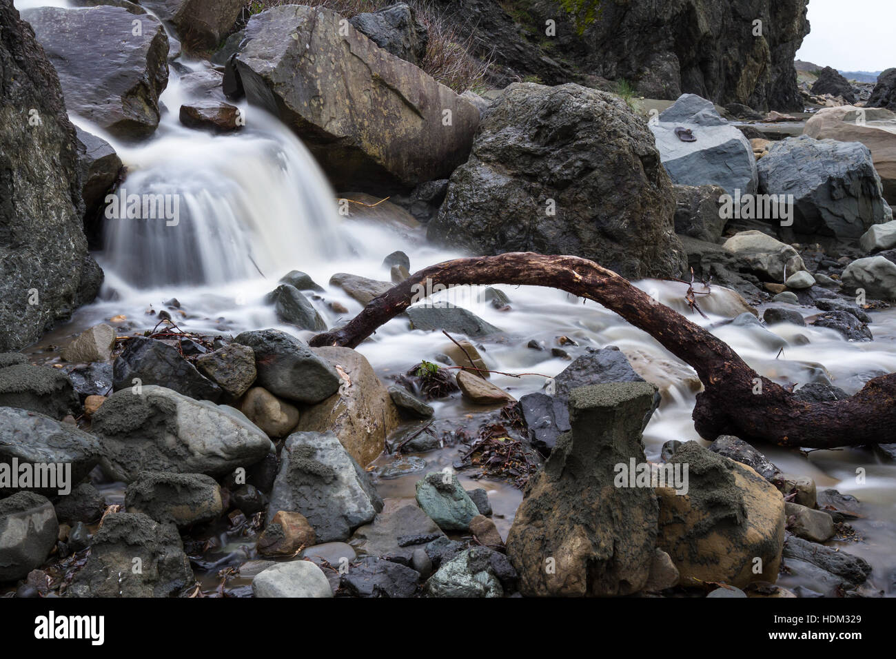 peaceful scene with a small waterfall rushing over rocks and making its ...