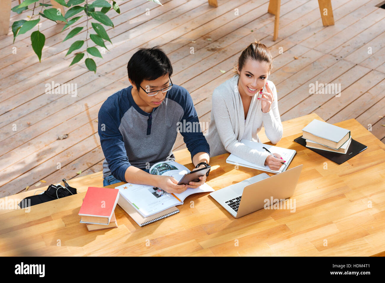 Two smiling young students using tablet and talking on cell phone in ...