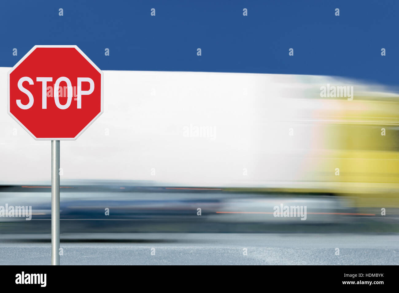 Red stop road sign, motion blurred truck vehicle traffic in background ...