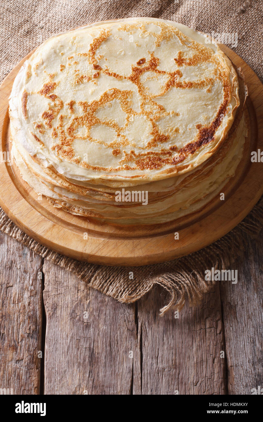 pile of crepes on a kitchen board on the table closeup. Vertical top ...