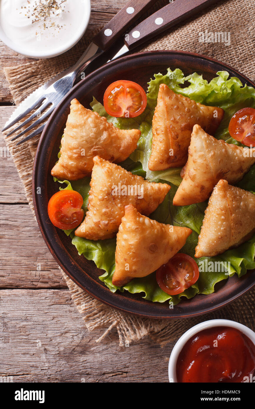 samosa on a plate with sauce and tomatoes closeup. vertical view from ...