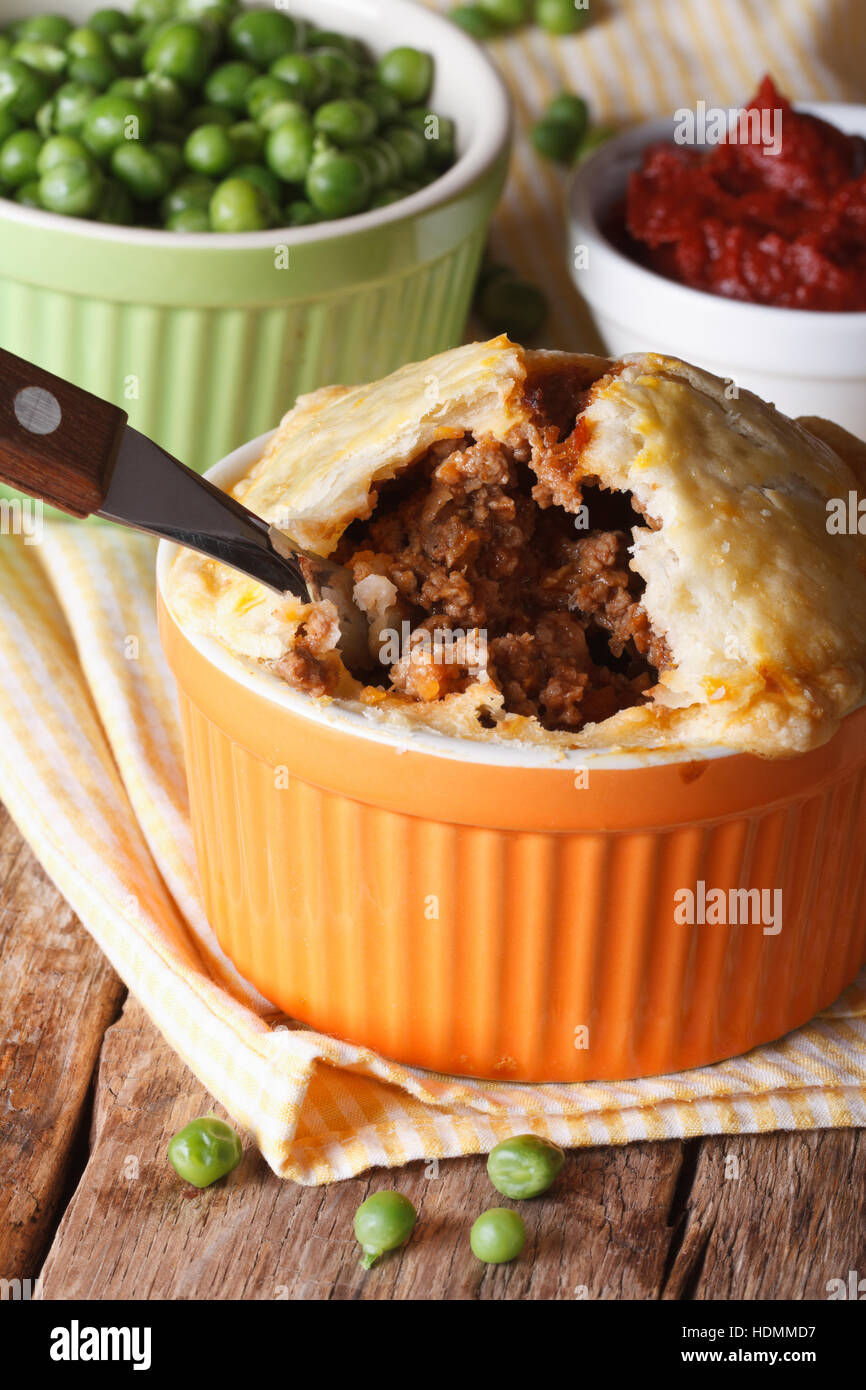 Delicious meat pie in a pot and green pea. Vertical close-up, rustic ...