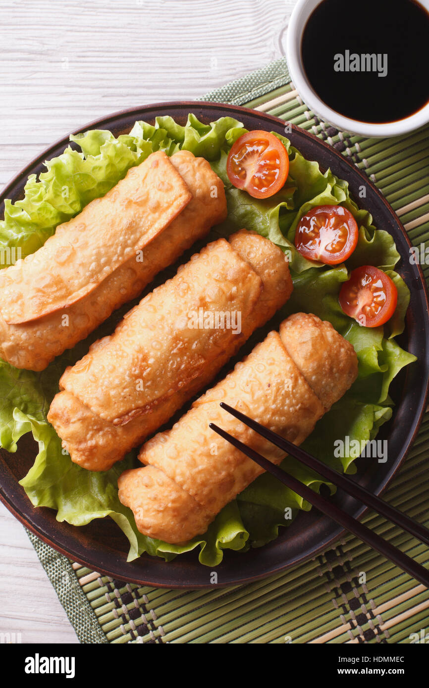spring rolls fried on lettuce leaves in a plate close-up, vertical view ...
