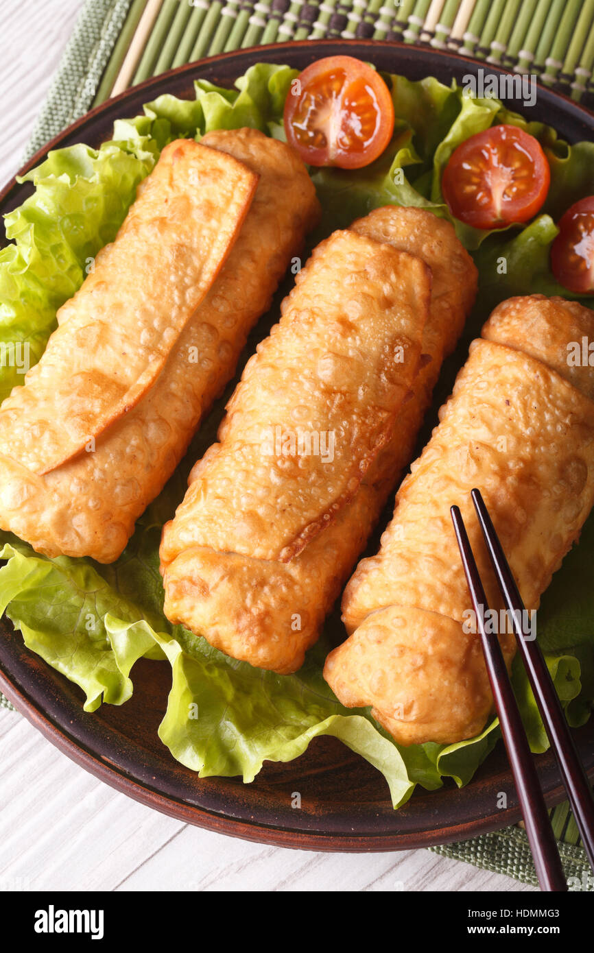 Asian spring rolls fried on a plate with lettuce and tomatoes close up ...