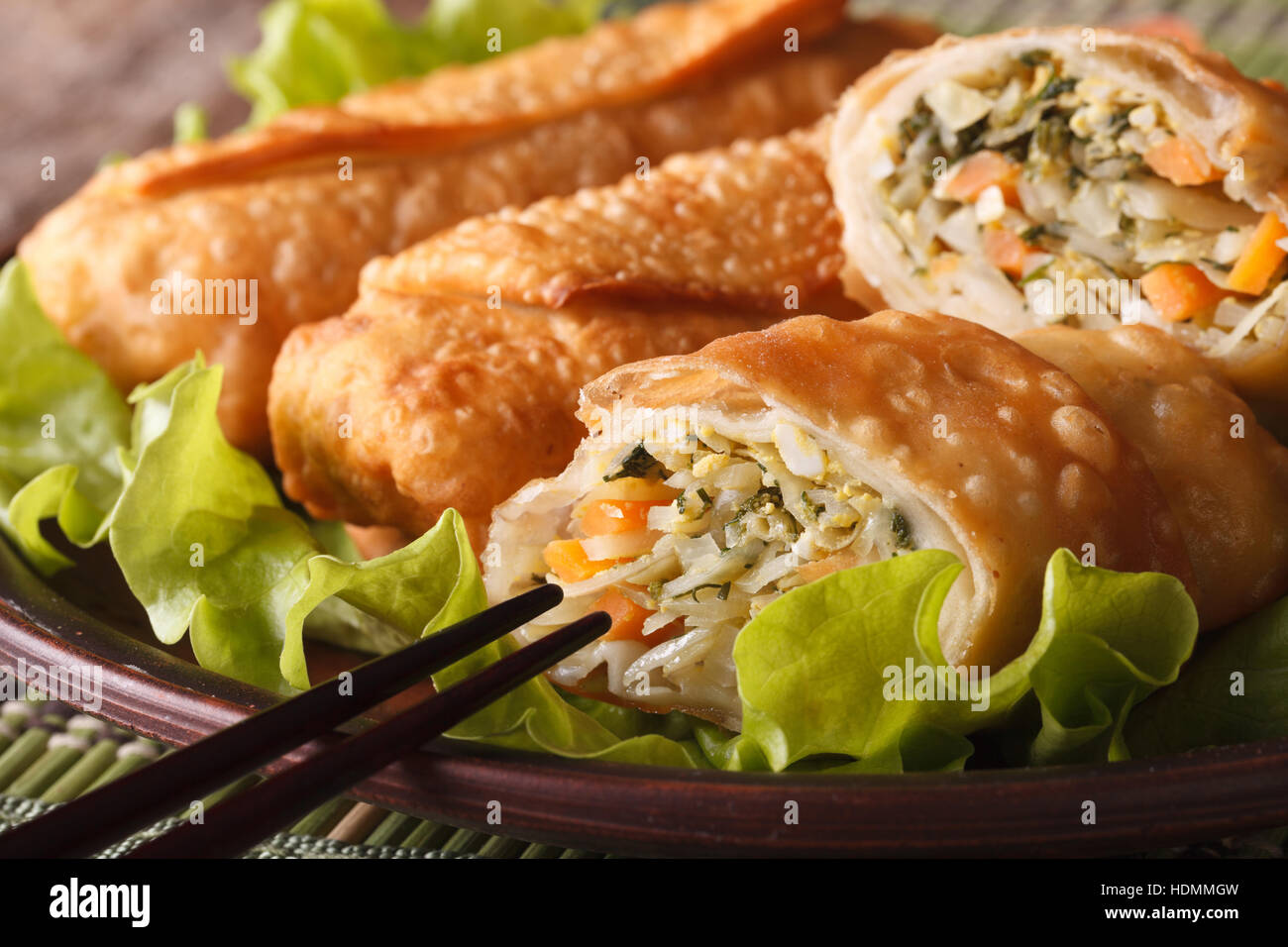 Asian fried spring rolls sliced on a plate macro and chopsticks ...