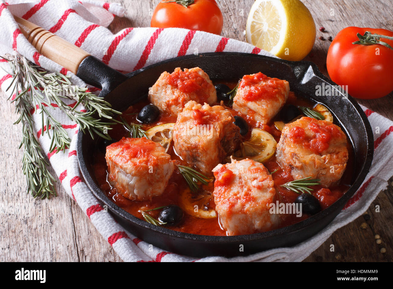 Pieces of fish in tomato sauce in a pan and ingredients on the table ...