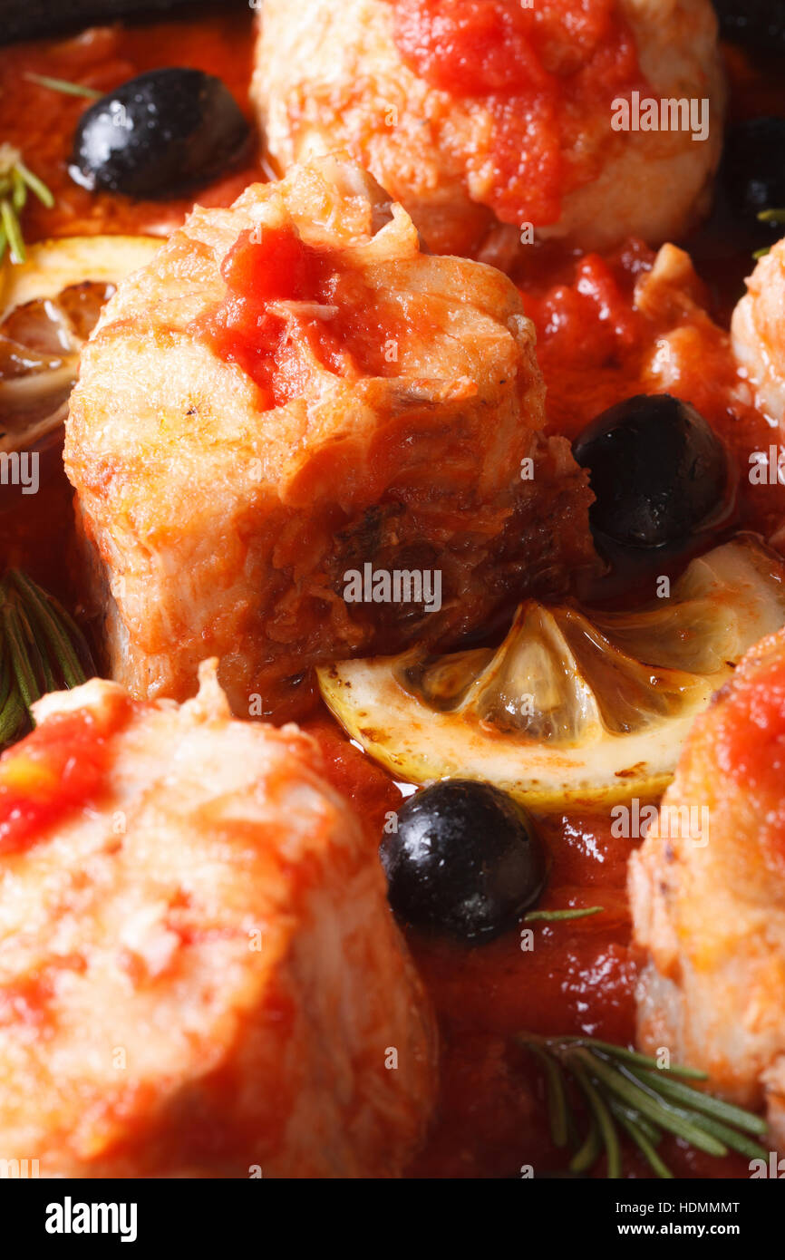 Fish fillet in tomato sauce with lemon and olives macro. Vertical view ...
