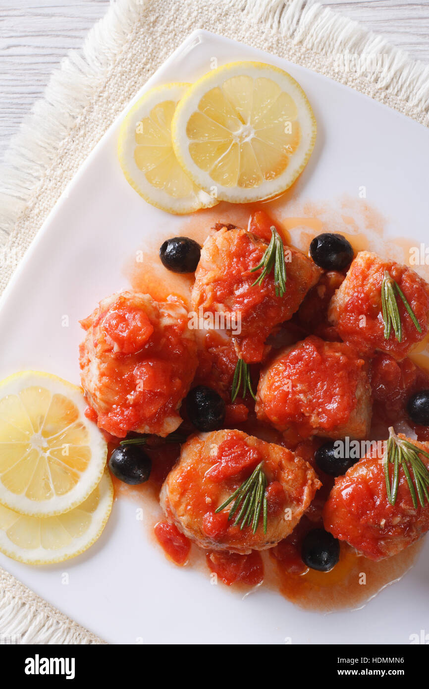 Fish fillet in tomato sauce with olives on the plate. vertical top view ...