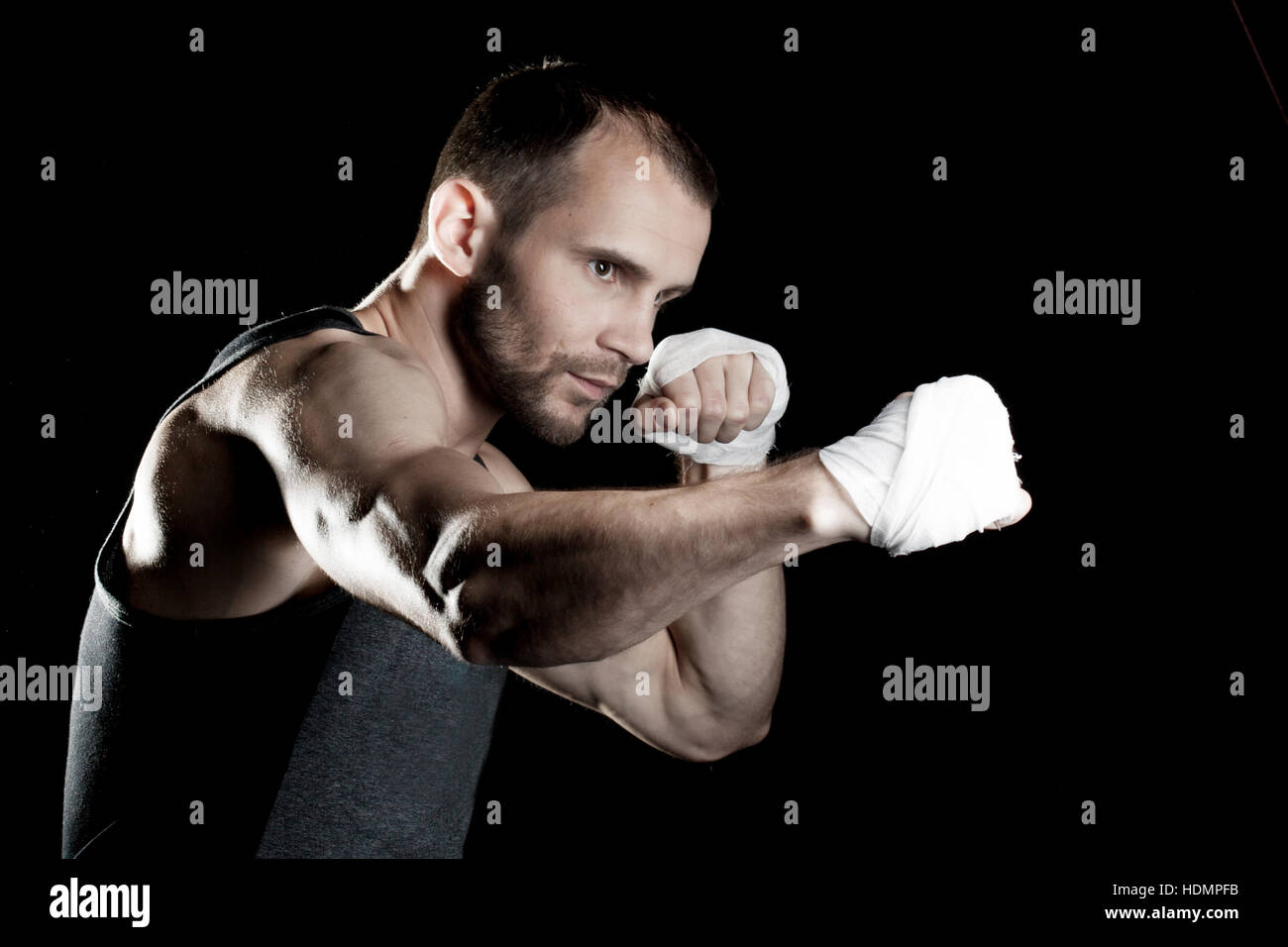 muscular man on a black background, clasps hands in a fist Stock Photo ...
