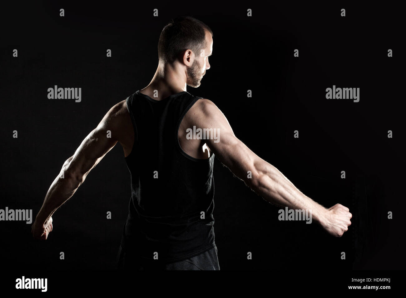 muscular man on a black background, clasps hands in a fist Stock Photo ...
