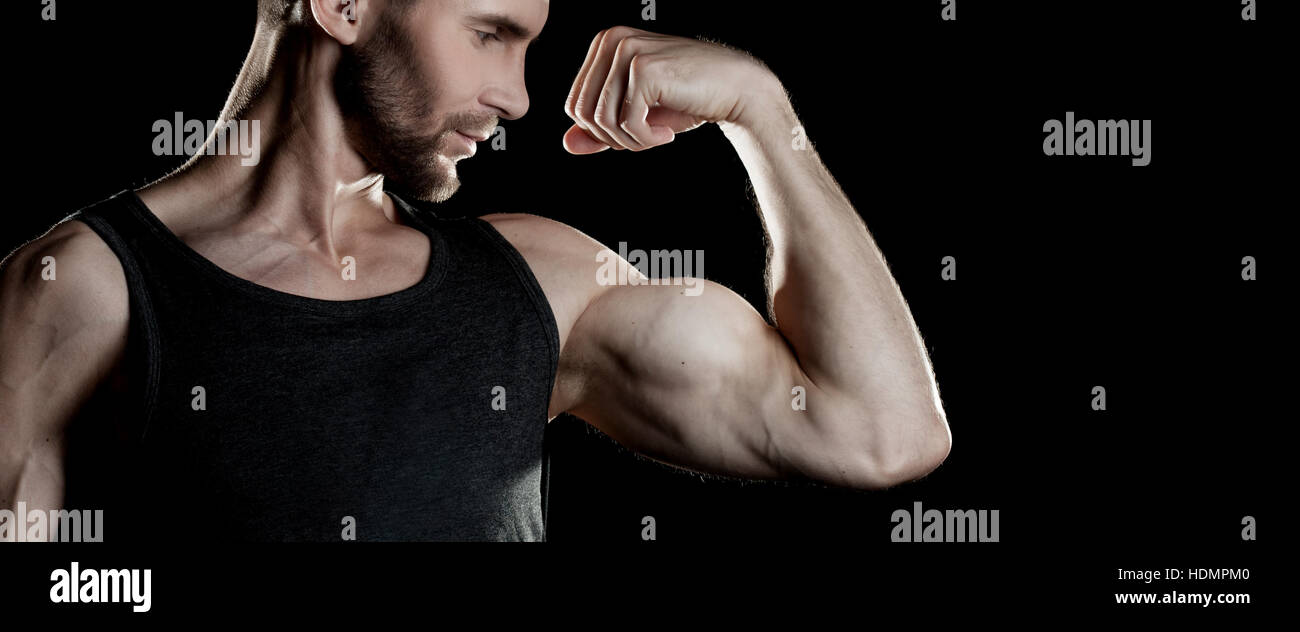 muscular man on a black background, clasps hands in a fist Stock Photo ...