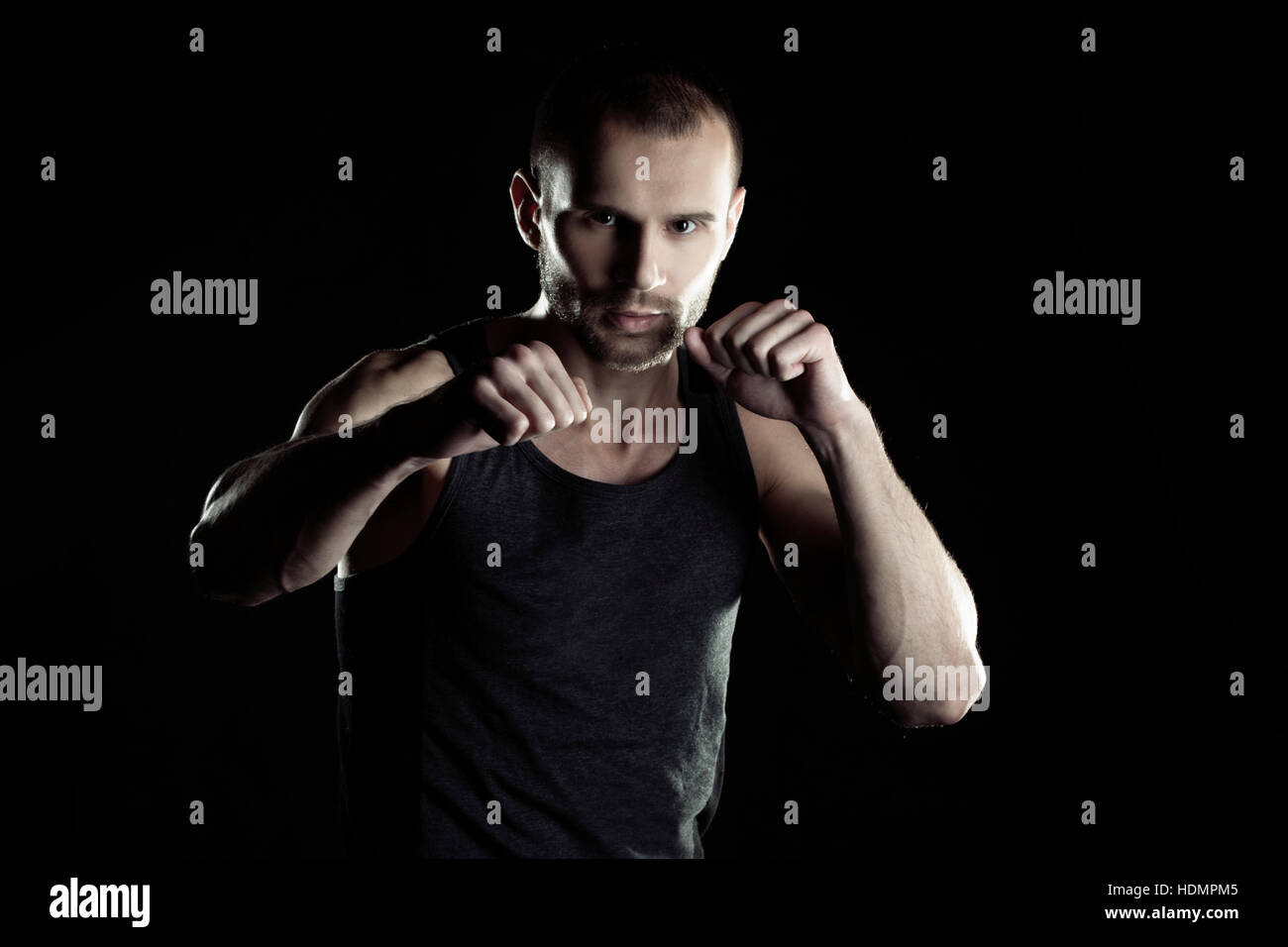 muscular man on a black background, clasps hands in a fist Stock Photo ...