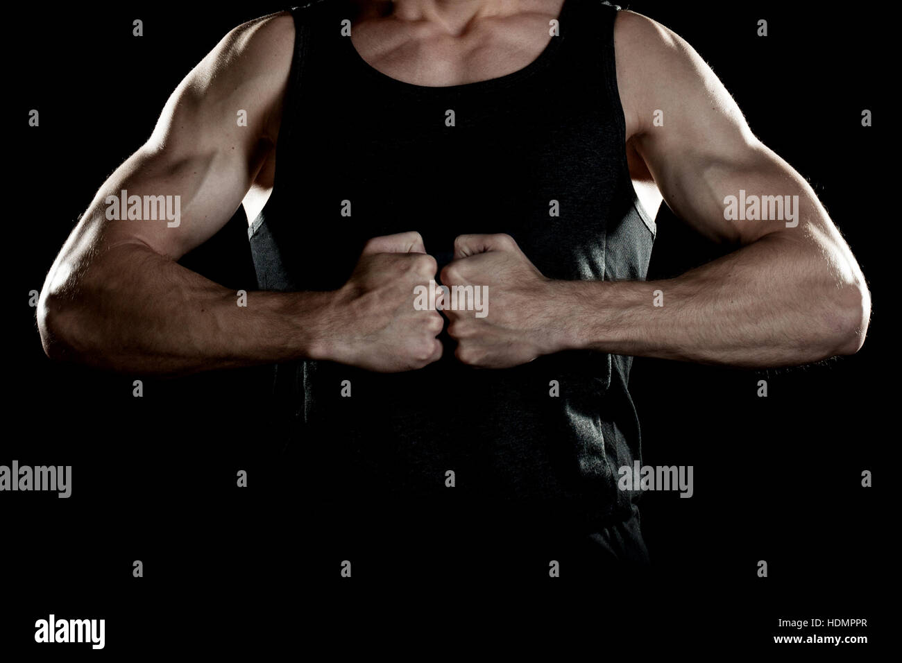 muscular man on a black background, clasps hands in a fist Stock Photo ...