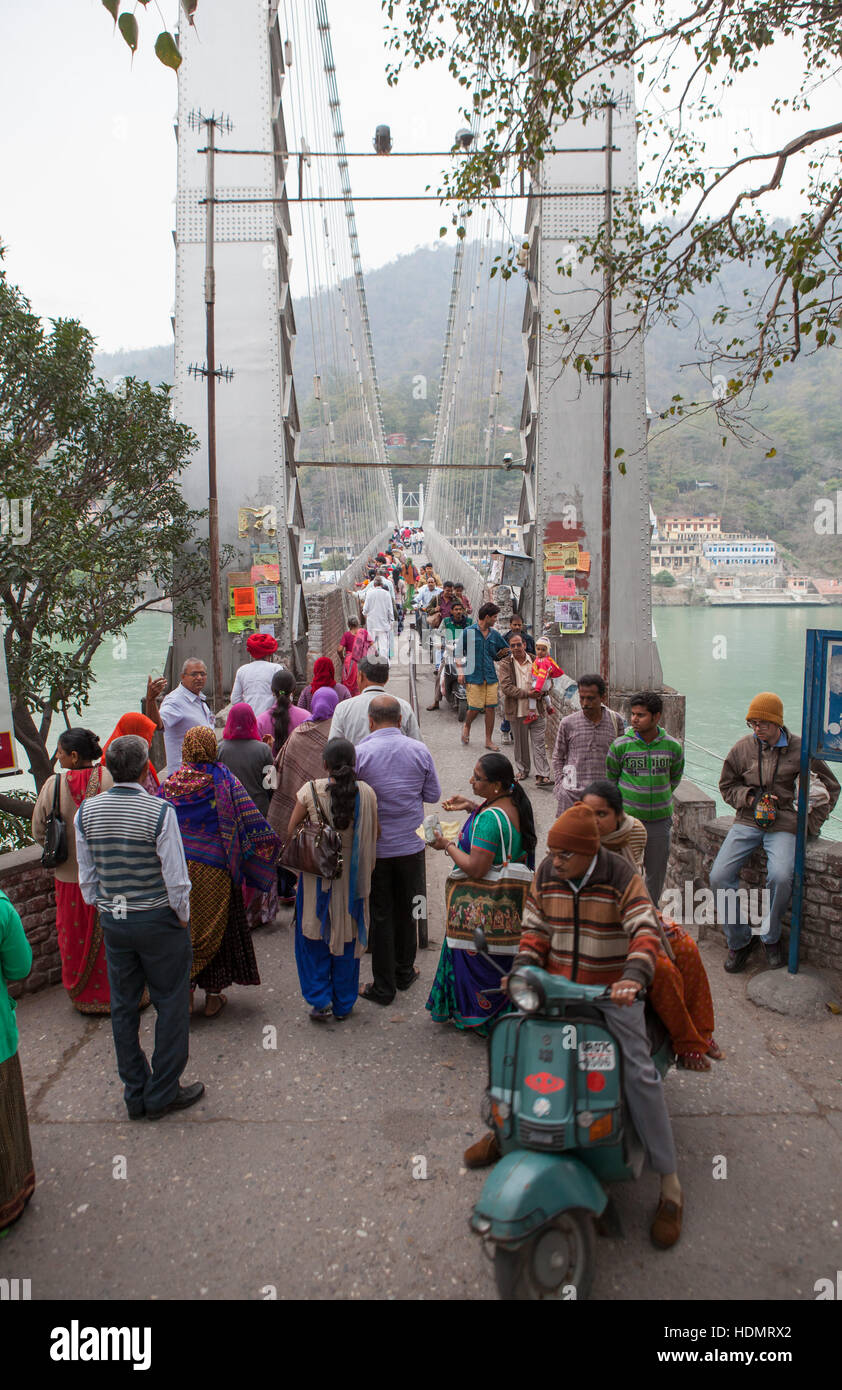 People crossing Laxman Jhula bridge over Ganges river in Rishikesh ...