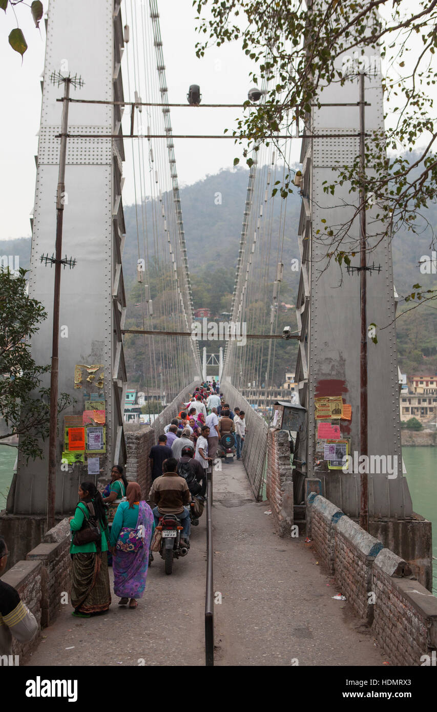 People crossing Laxman Jhula bridge over Ganges river in Rishikesh ...