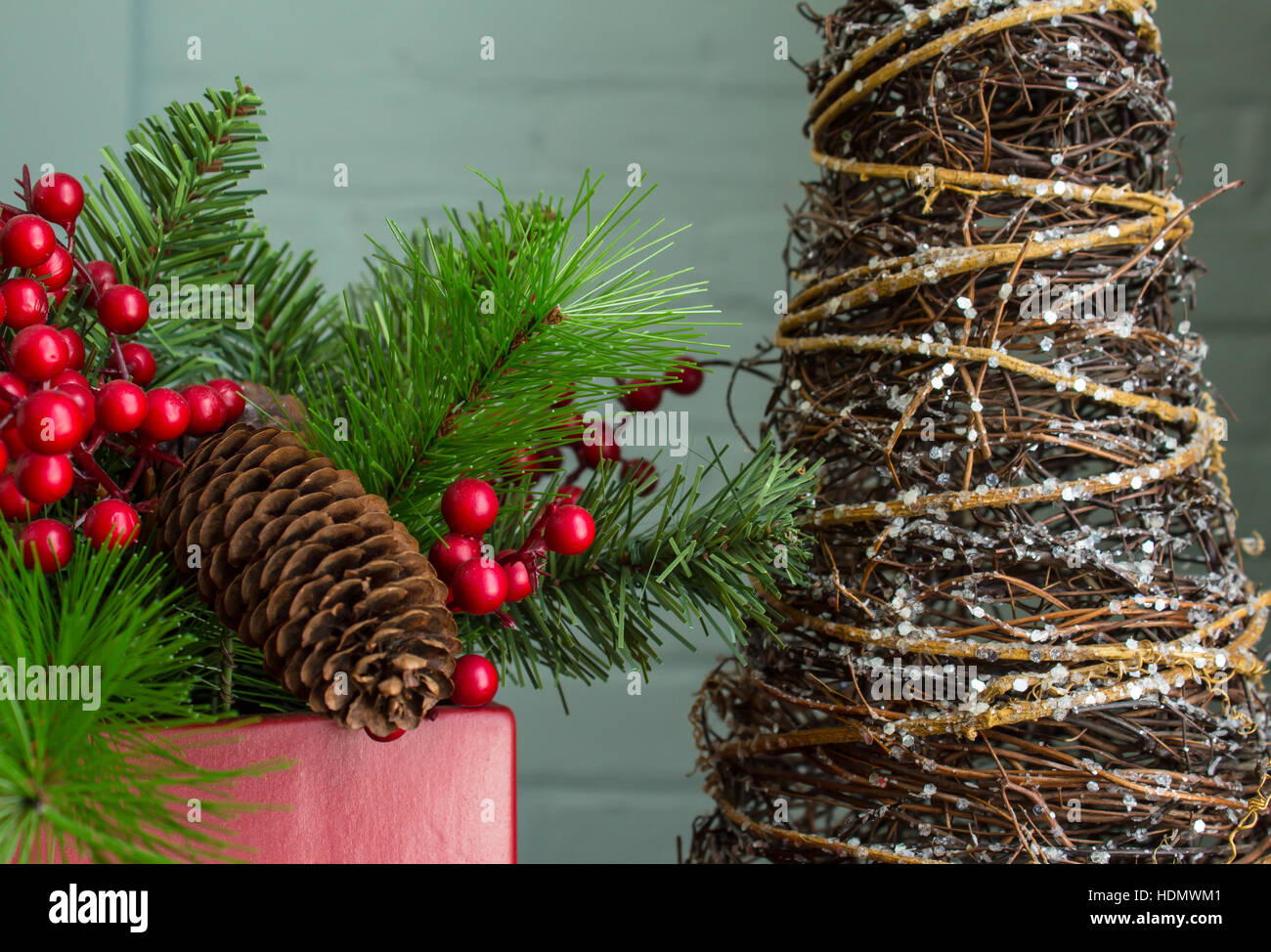 Evergreen, berries, and pinecones in a bright red pot with an abstract ...