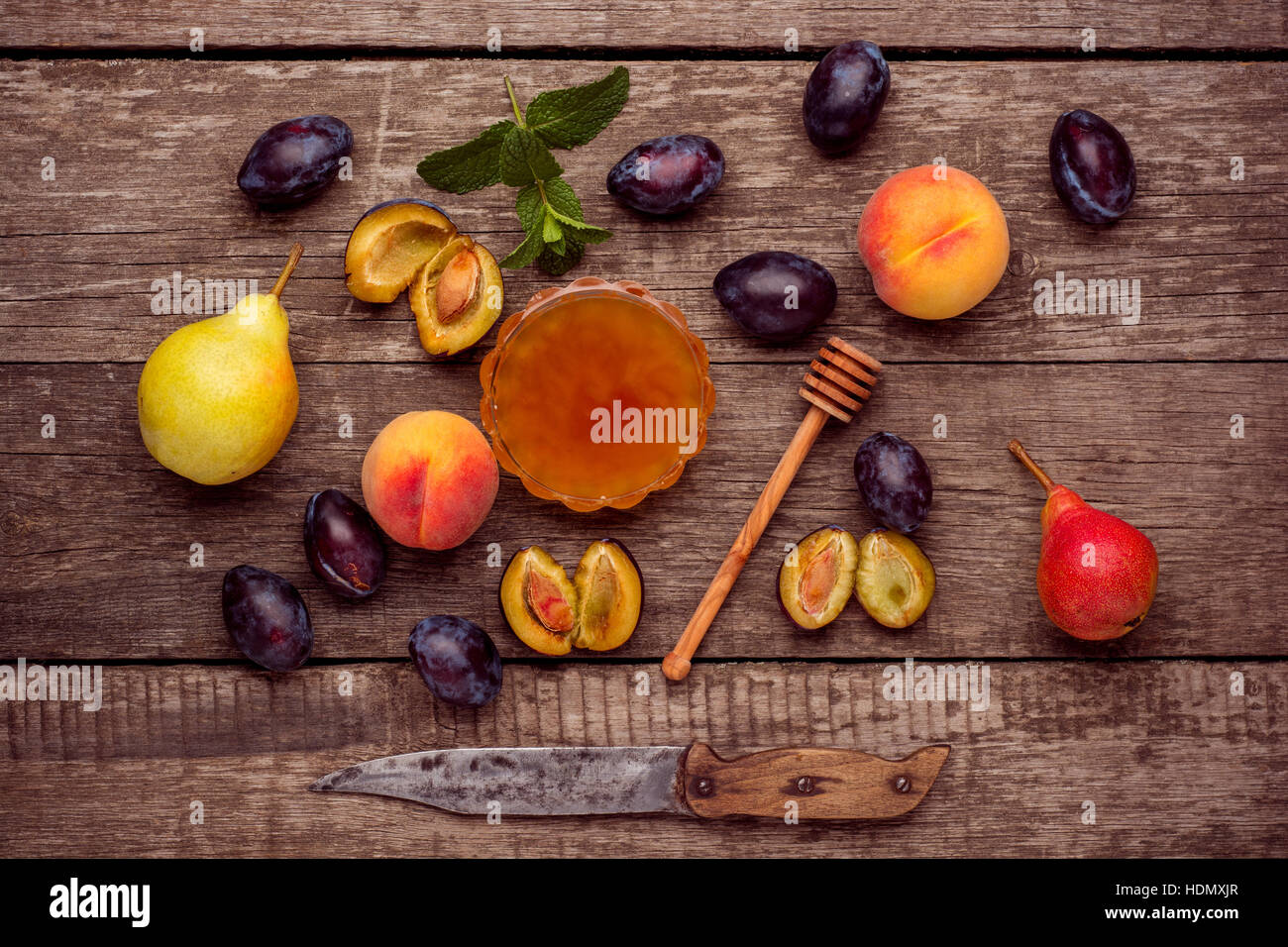 Ripe fruits of peach, plums and pear with honey in a tray on rustic ...
