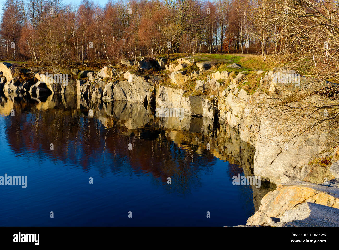 Water filled granite stone quarry in leafless forest in winter ...