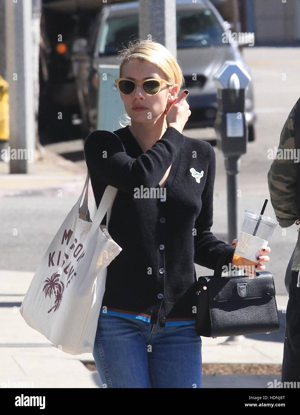 Emma Roberts picks up coffee wearing a black cardigan and cropped denim ...
